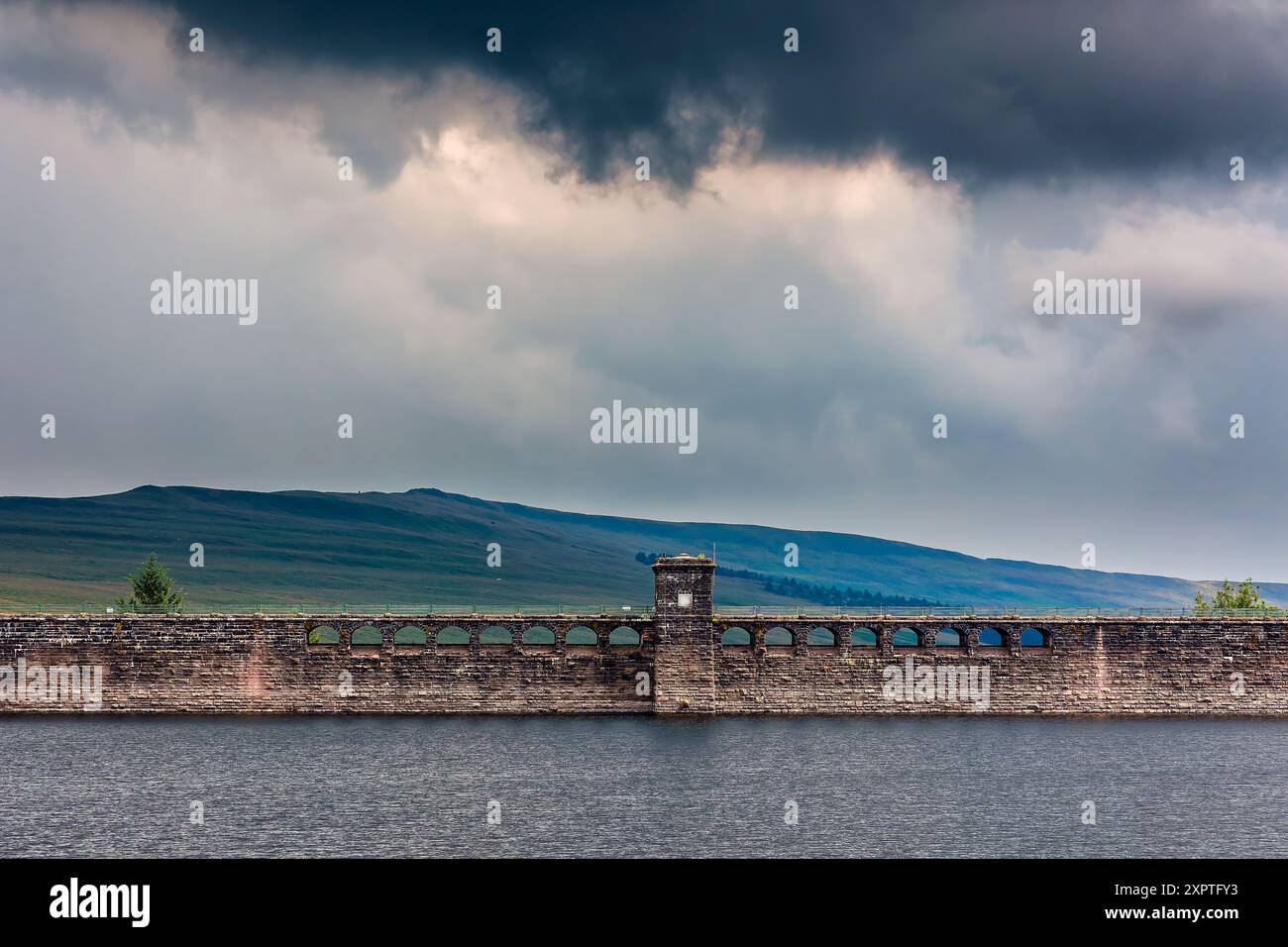 Dam wall of an old reservoir in a rural landscape on a stormy day ...