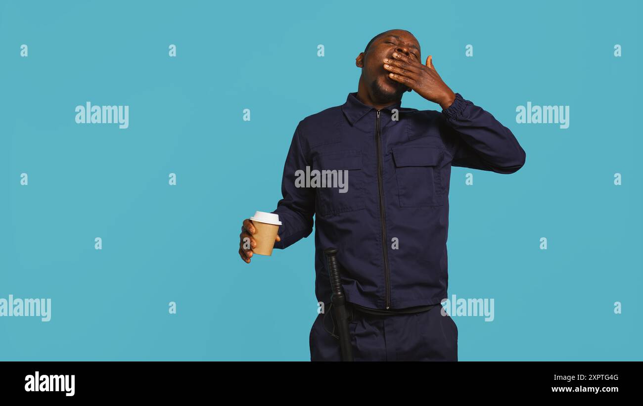 Tired security guard drinking coffee cup to stay awake, being tasked ...