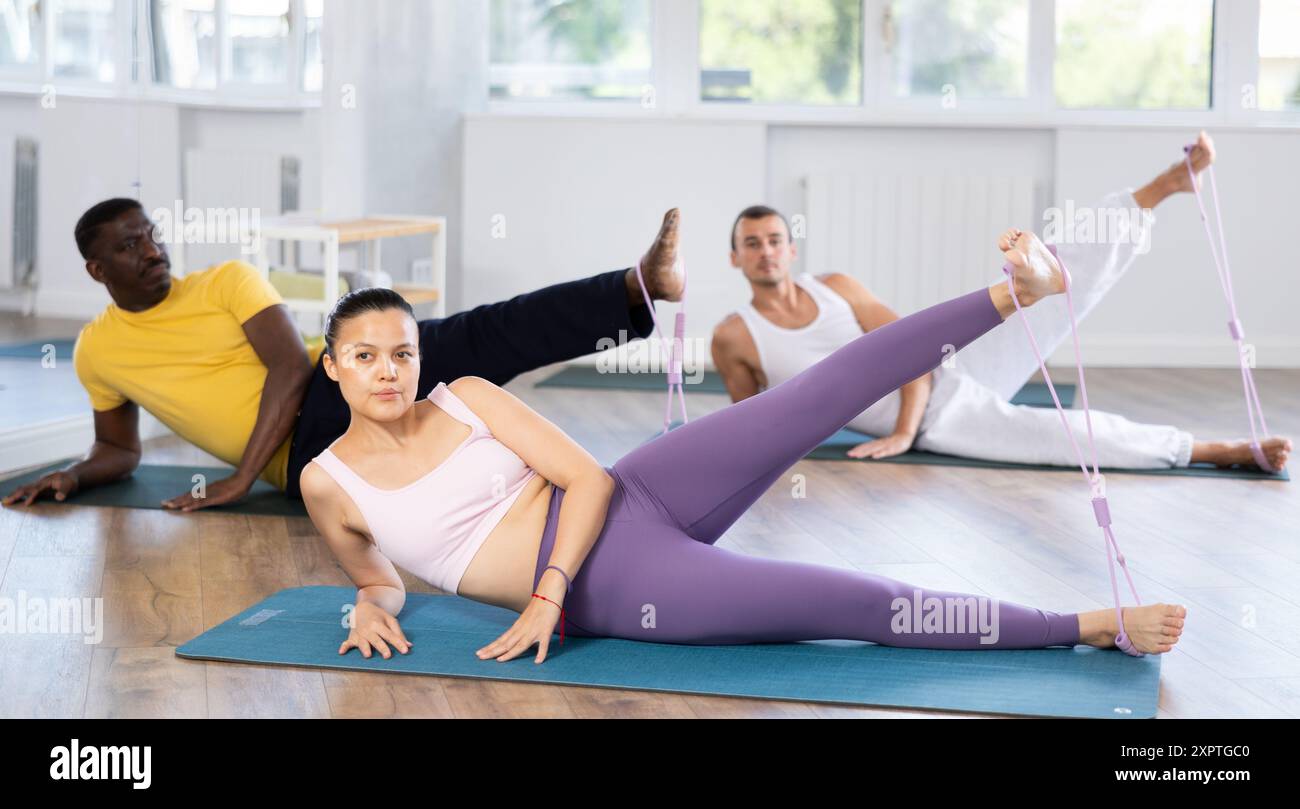 Pilates class - group of people of different nationalities doing leg ...