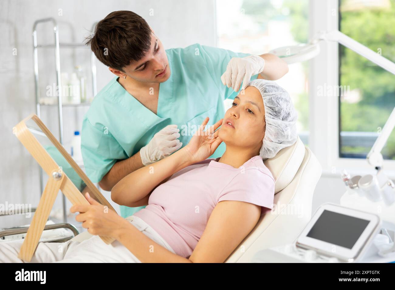 Young male cosmetologist examines face of young woman Stock Photo - Alamy