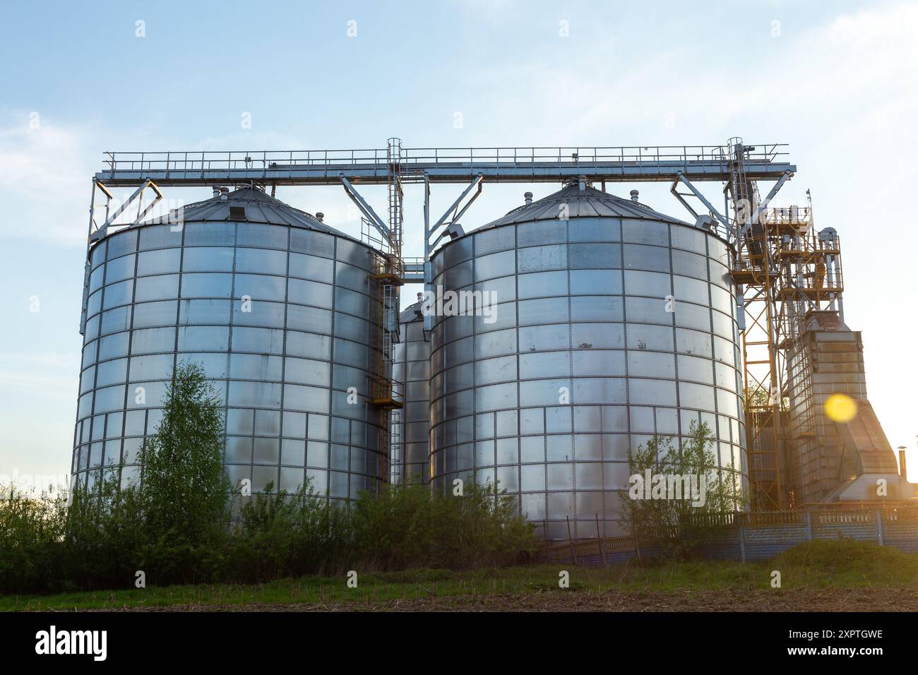 Agricultural silos next to harvested field in sunset . Set of storage ...