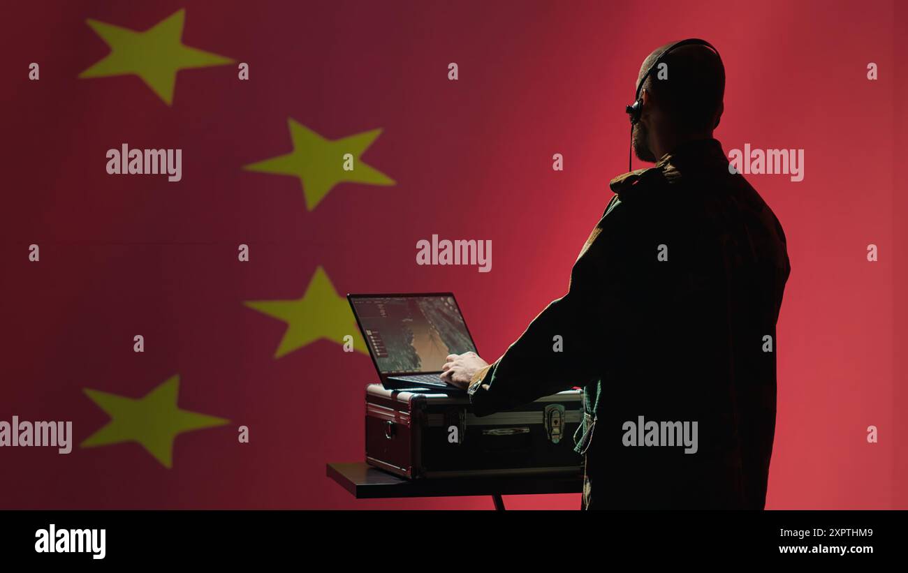 Chinese army military dispatcher looking at surveillance transmission on laptop, relaying ...