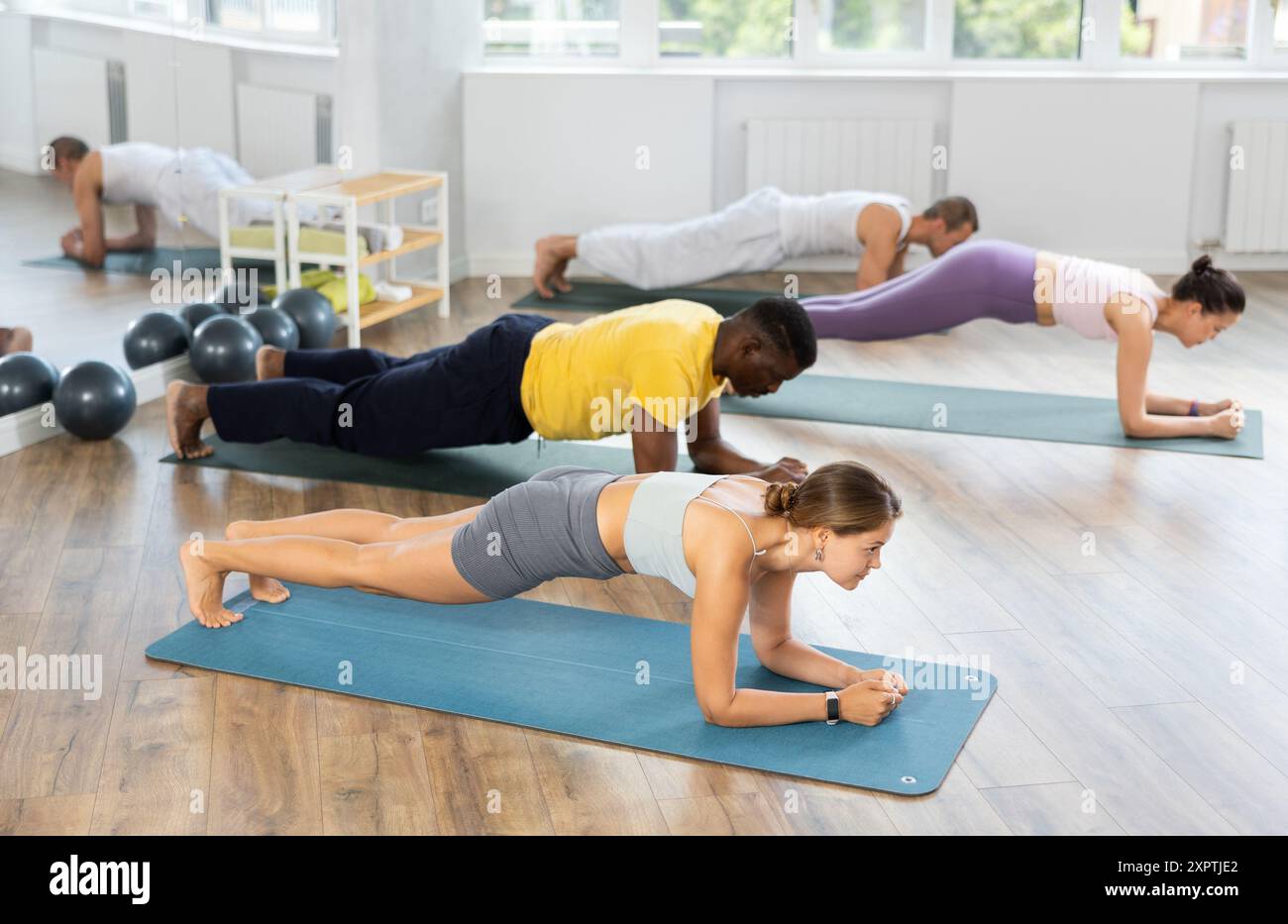 Group of multinational women and men performing plank exercise during ...