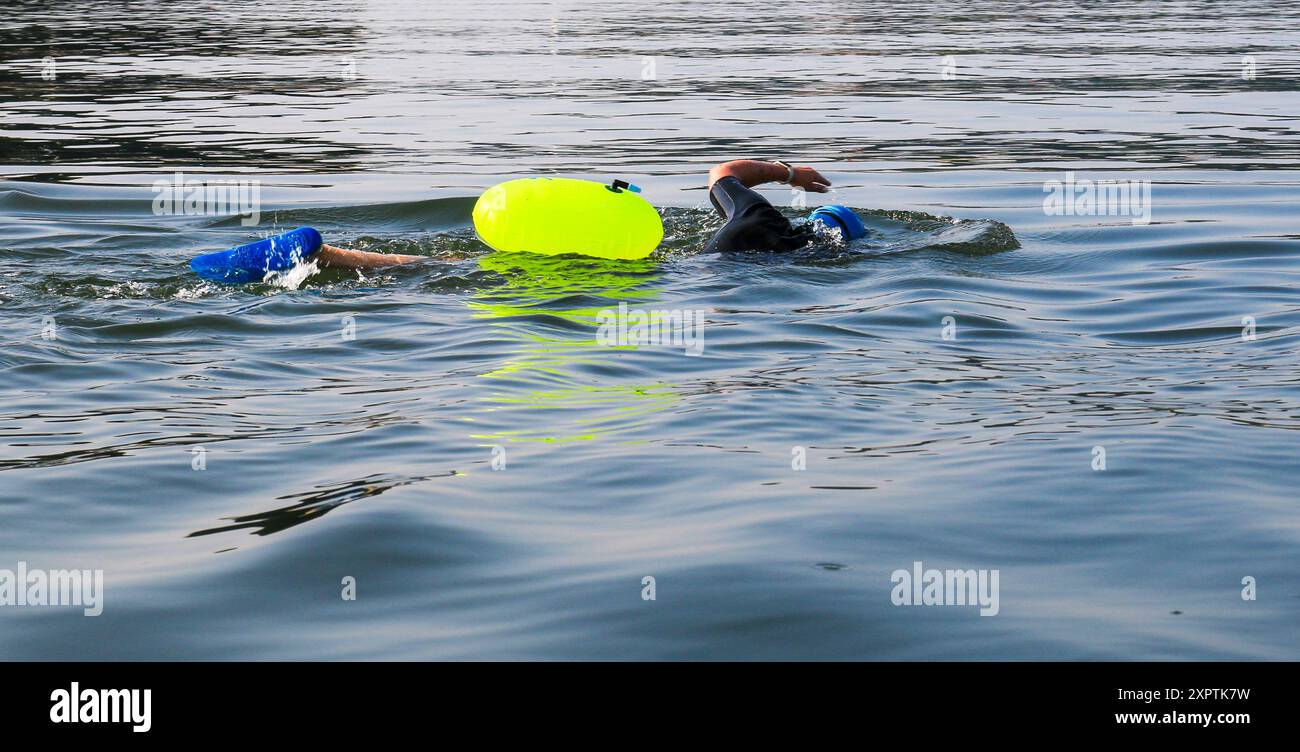 A close up of One swimmer swimming in the open water wearing a neon ...