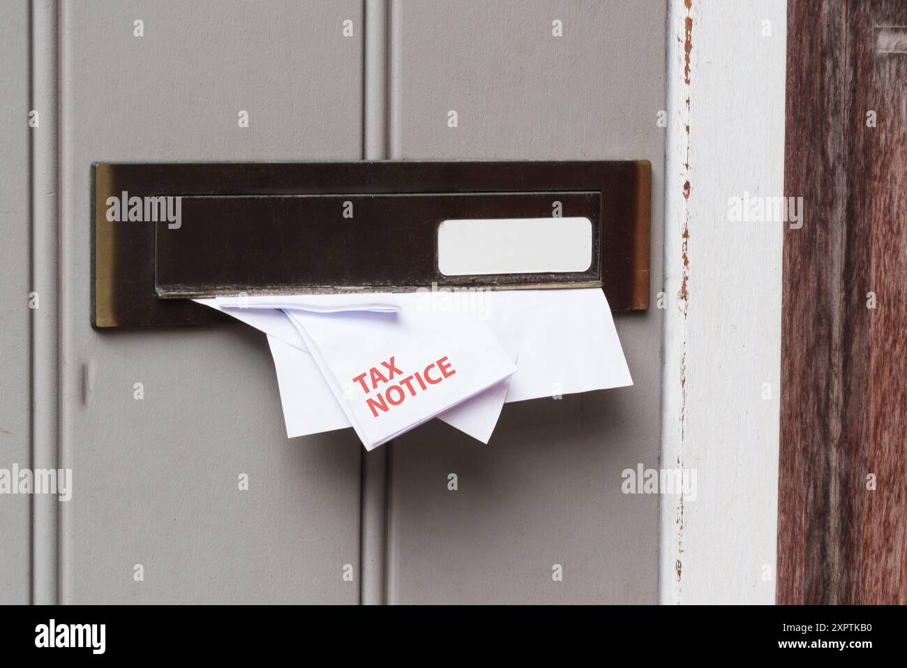 A tax notice letter is partially visible in a mail slot box, the ...