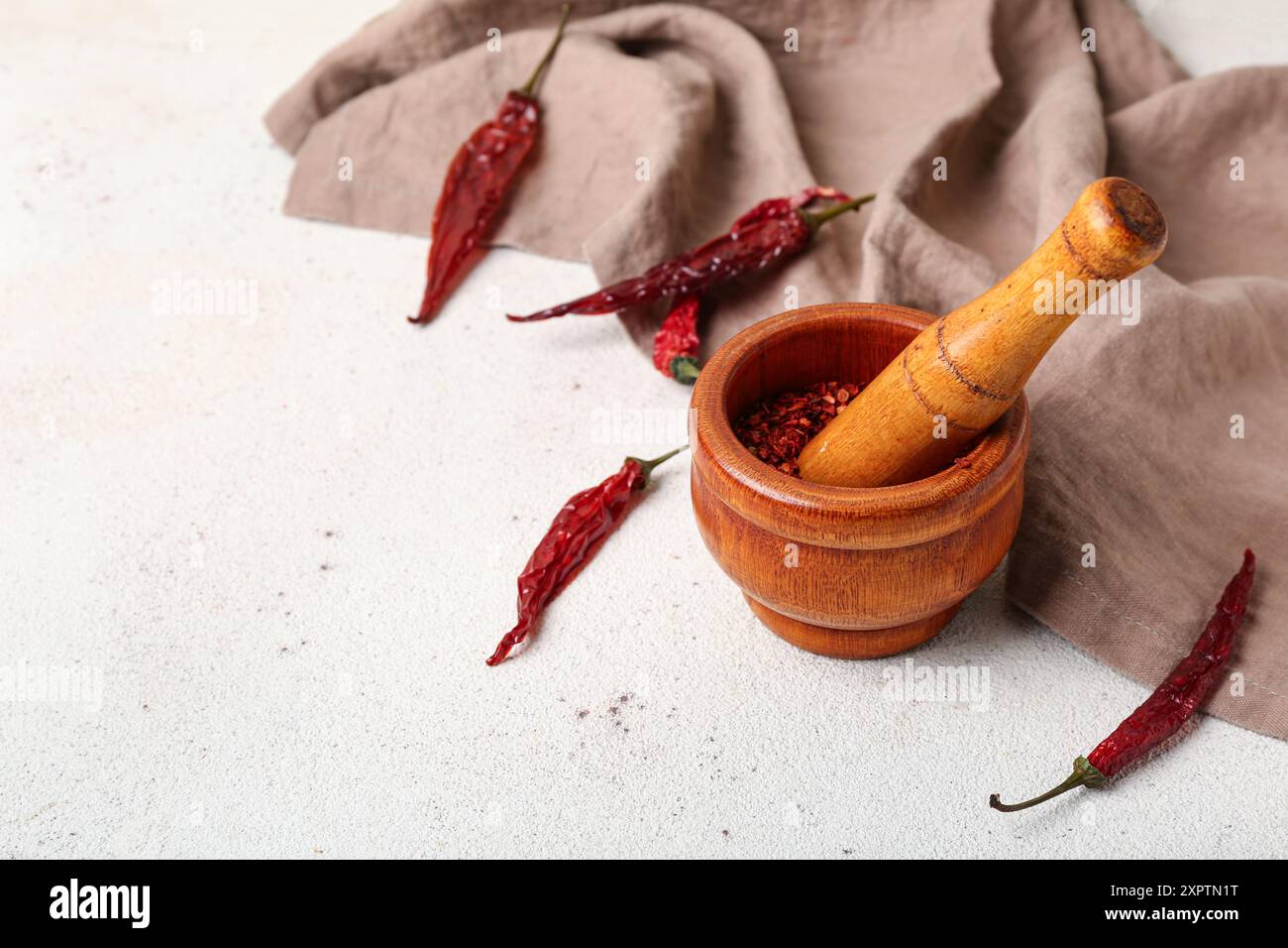 Wooden mortar and pestle with dry chili pepper on light background ...