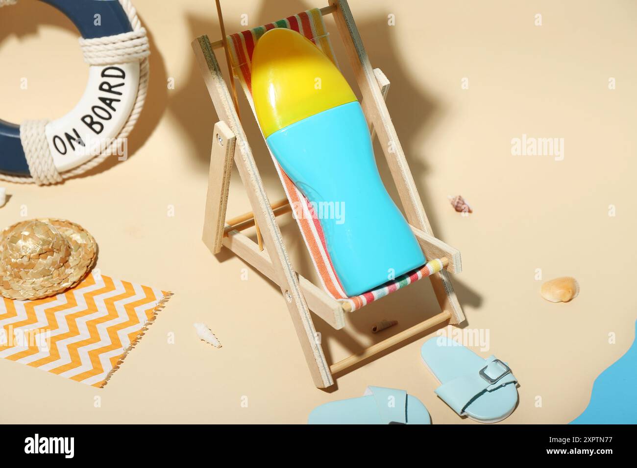Creative composition with miniature deckchair and sunscreen on beach ...