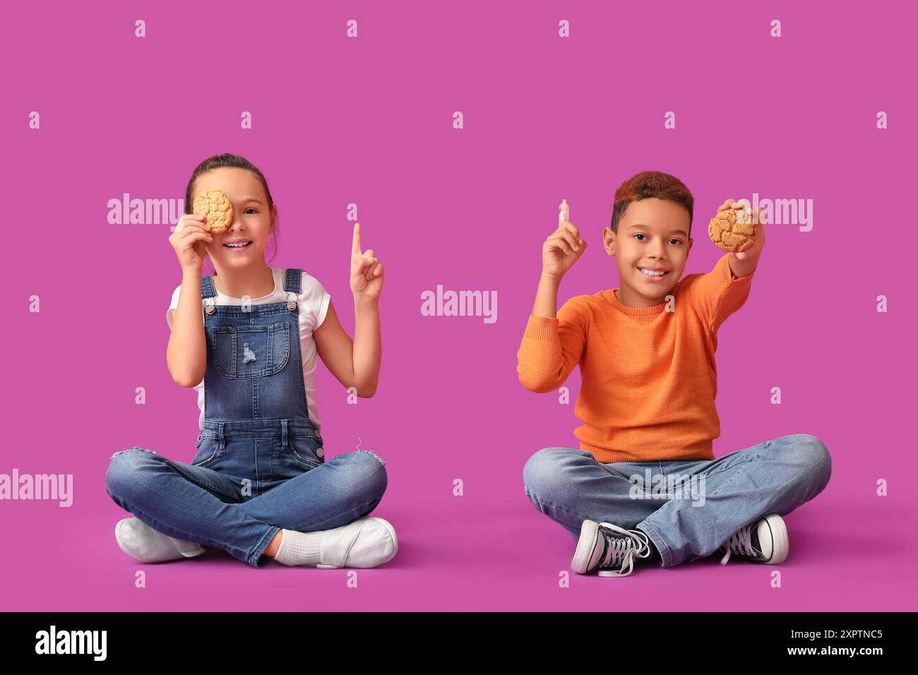 Little children with cookies pointing at something on purple background ...