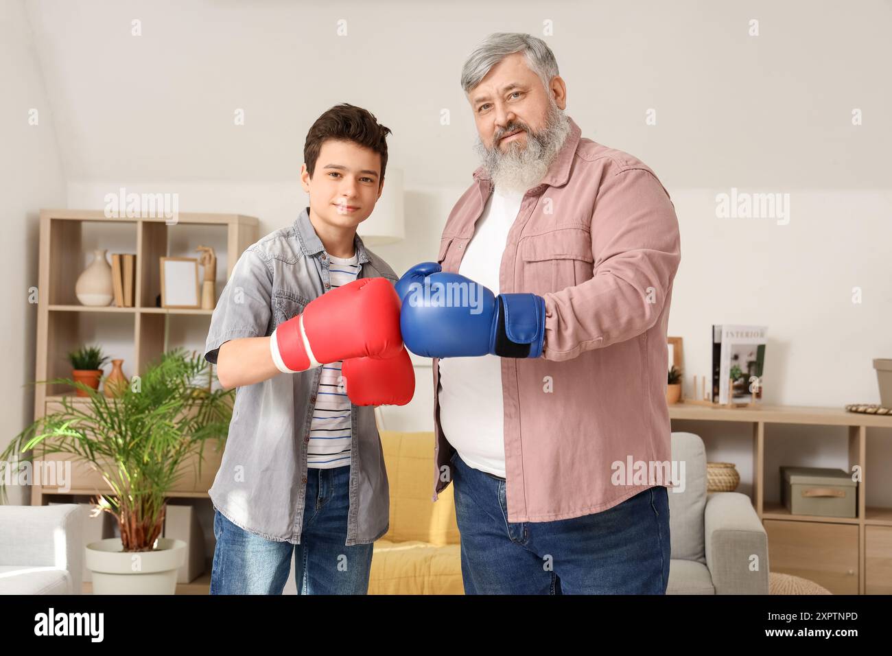 Happy grandfather and his cute grandson during boxing training at home ...