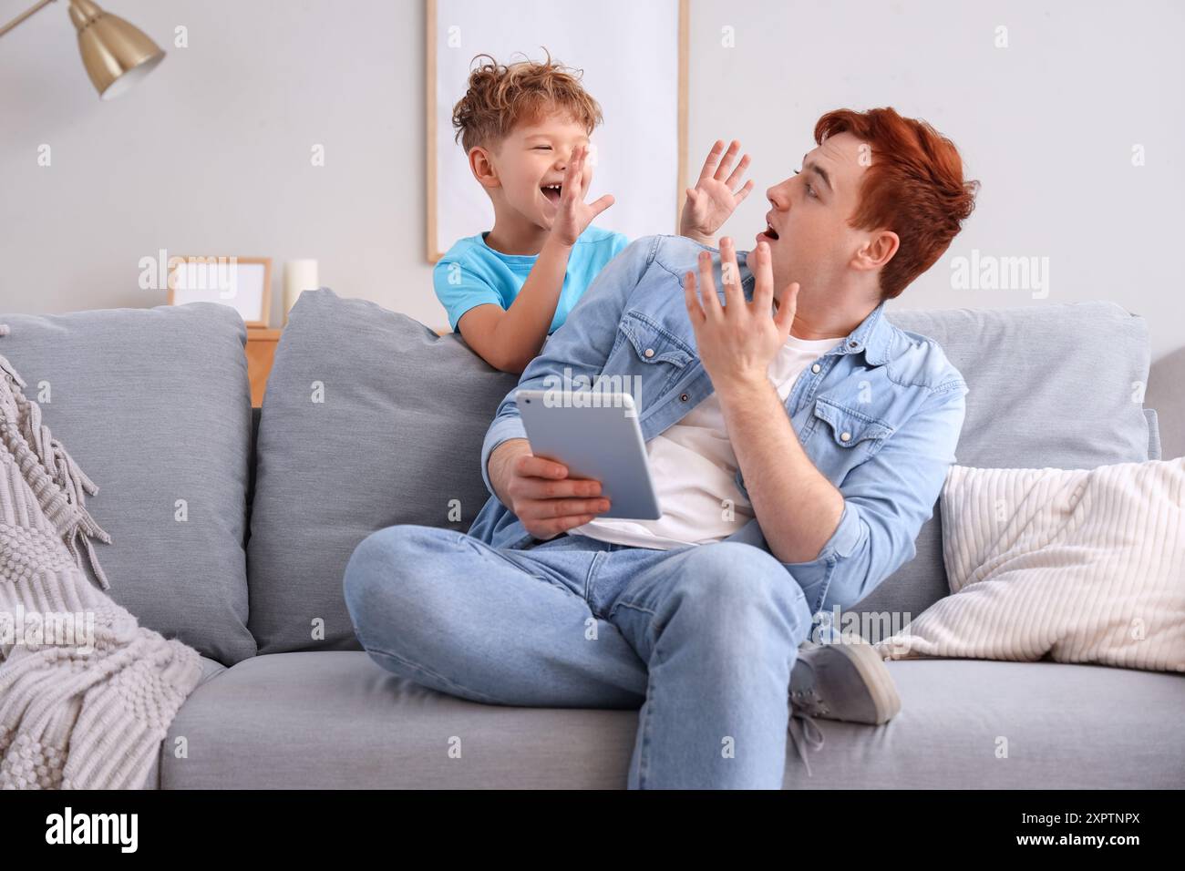 Little boy scaring his father with tablet computer at home Stock Photo ...