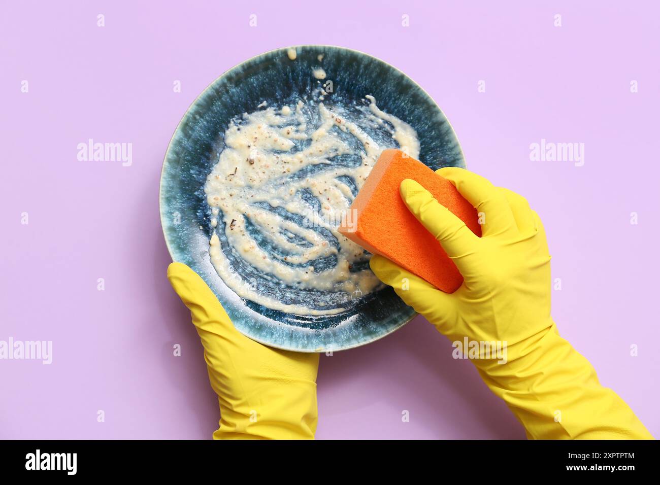 Hands washing dishes on lilac background Stock Photo - Alamy