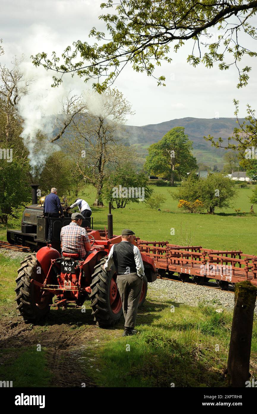 "Winifred" with a train of slate wagons passing a vintage tractor and ...