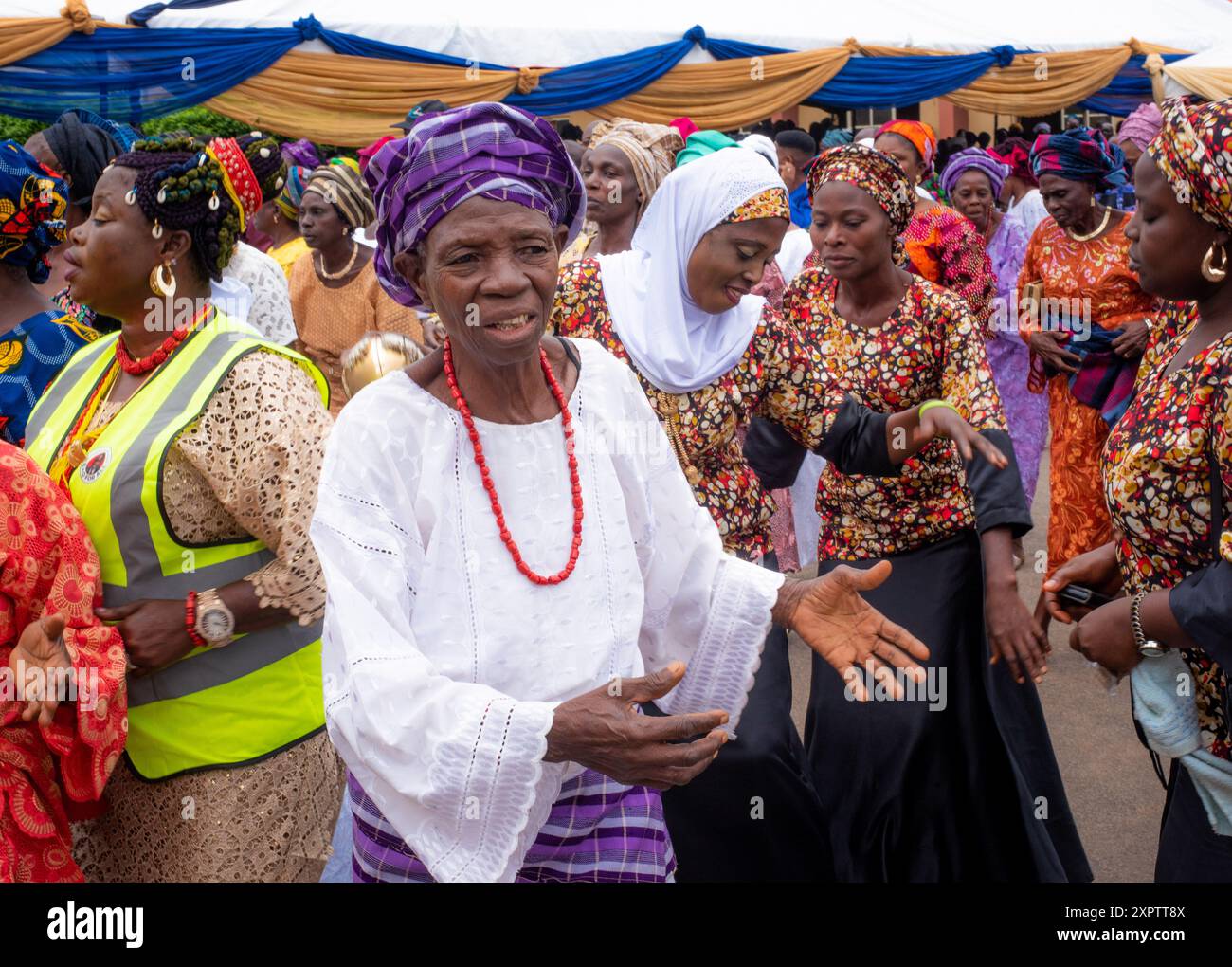 A woman in with and purple attire and red bead dance in celebration ...