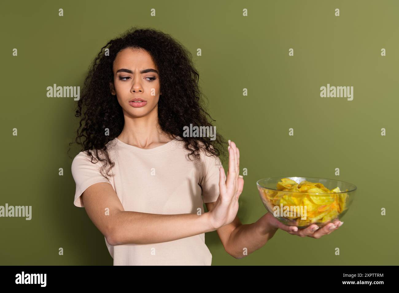 Photo of serious dissatisfied girl with wavy hairdo dressed beige t ...
