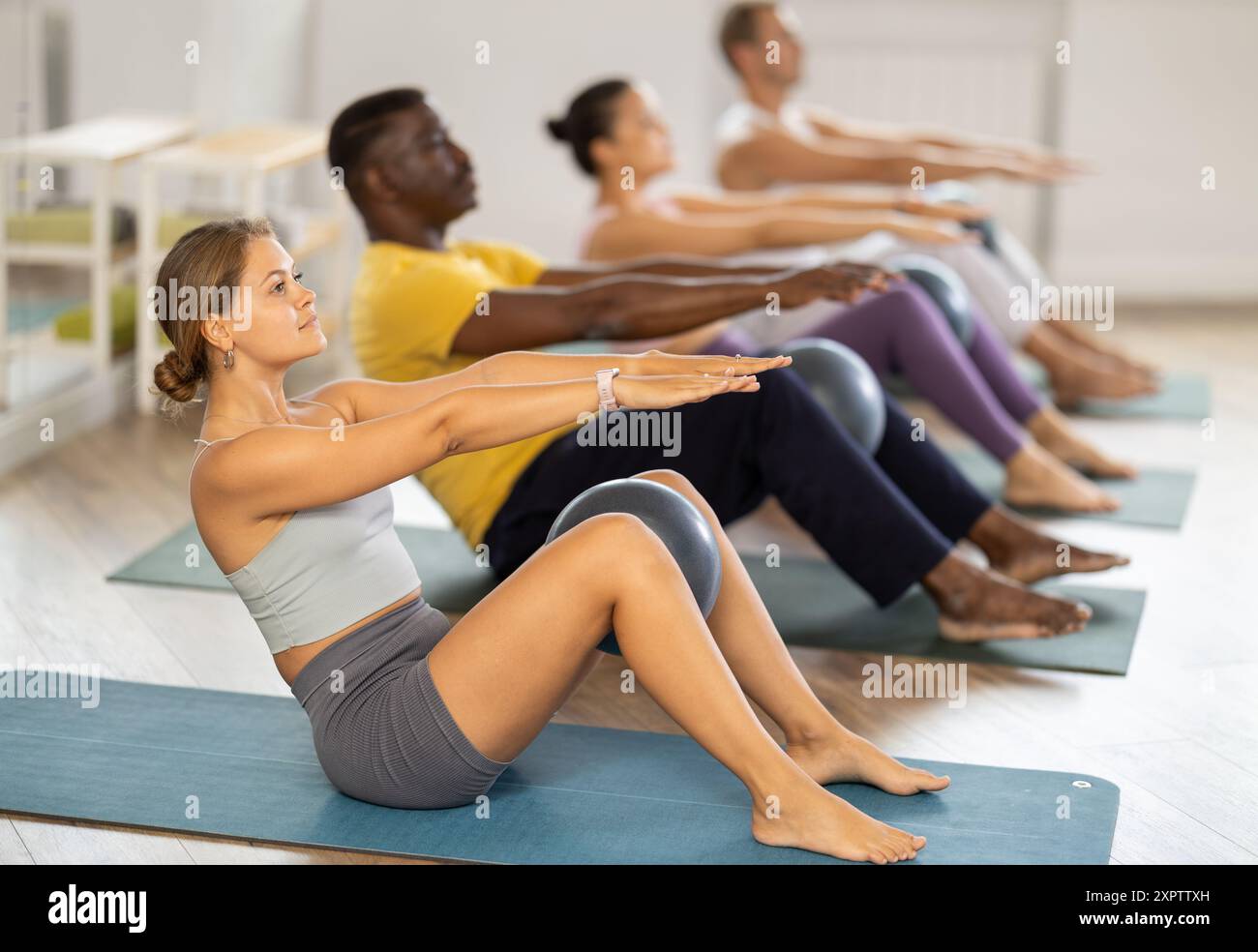 Multiethnic group of people doing exercises for press with pilates ball ...