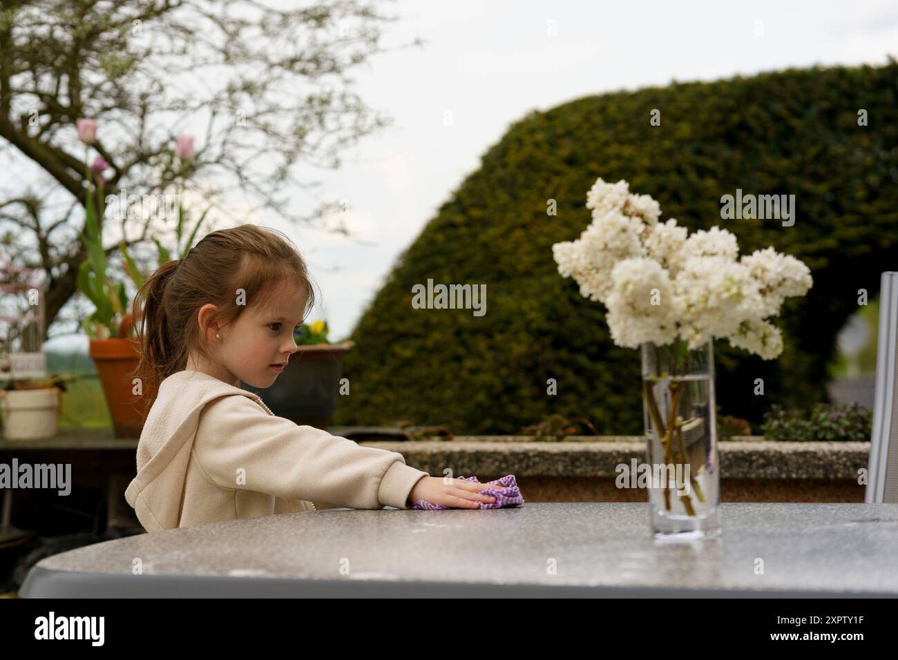 Little cute girl wiping table on terrace of country house. Concept of ...