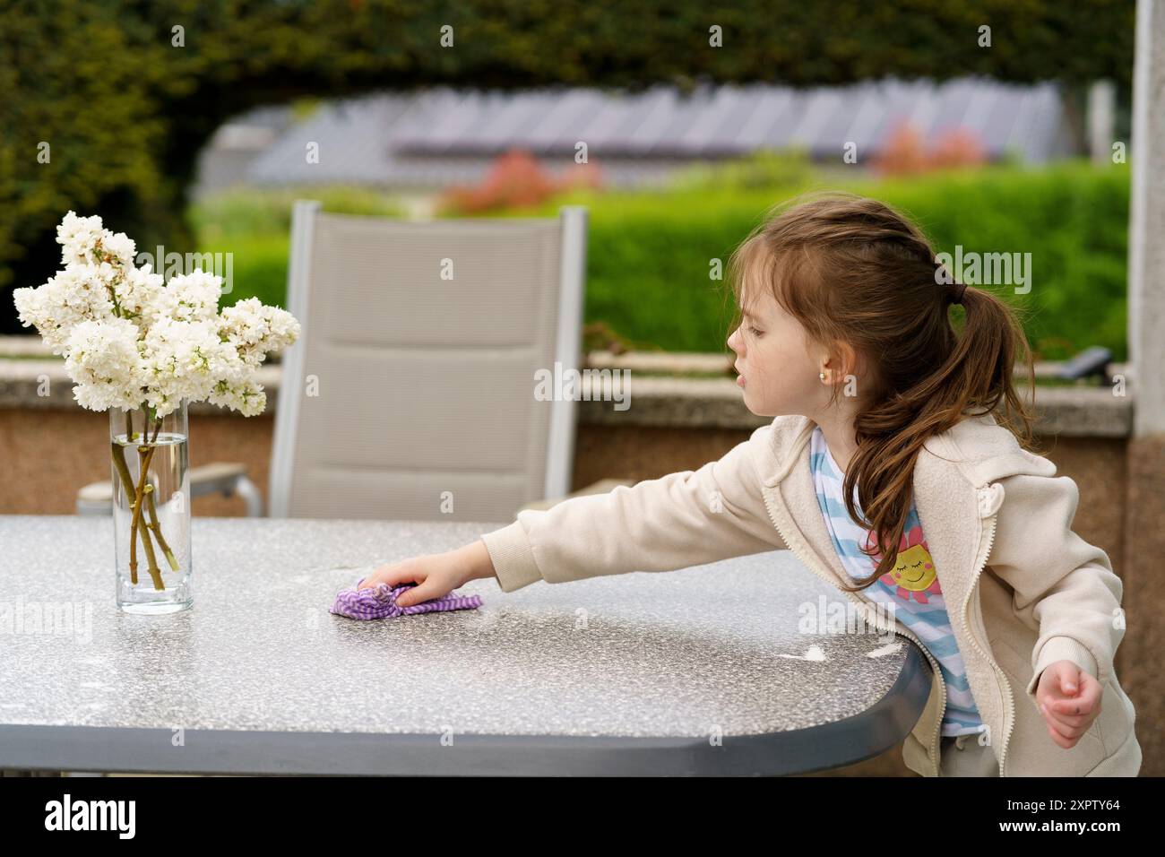Little cute girl wiping table on terrace of country house. Concept of ...