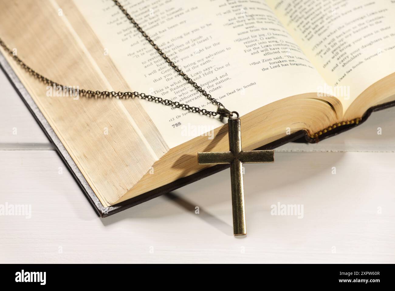 Cross with chain and Bible on white wooden table, closeup. Religion of ...