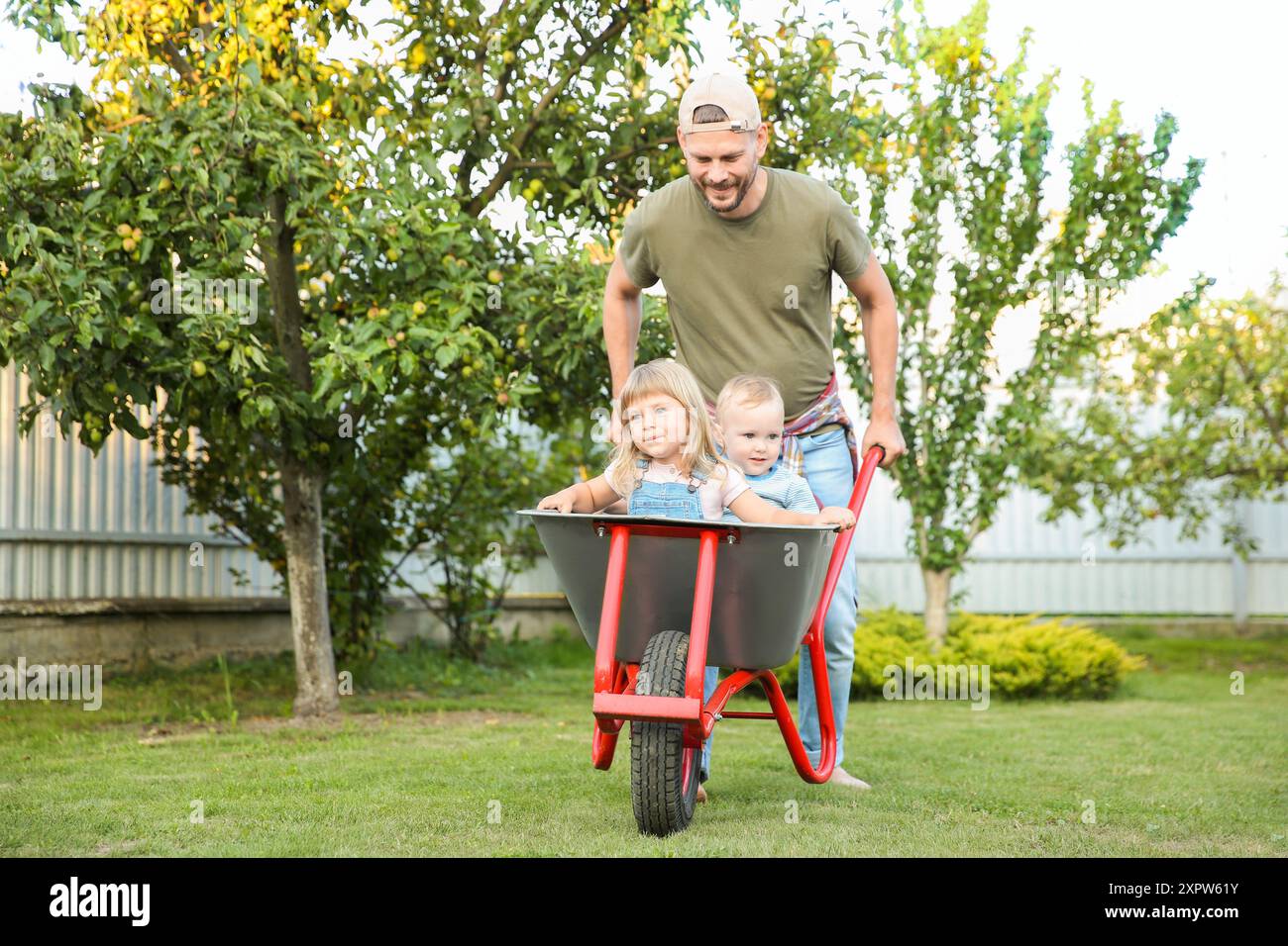 Father pushing wheelbarrow with his kids outdoors Stock Photo - Alamy