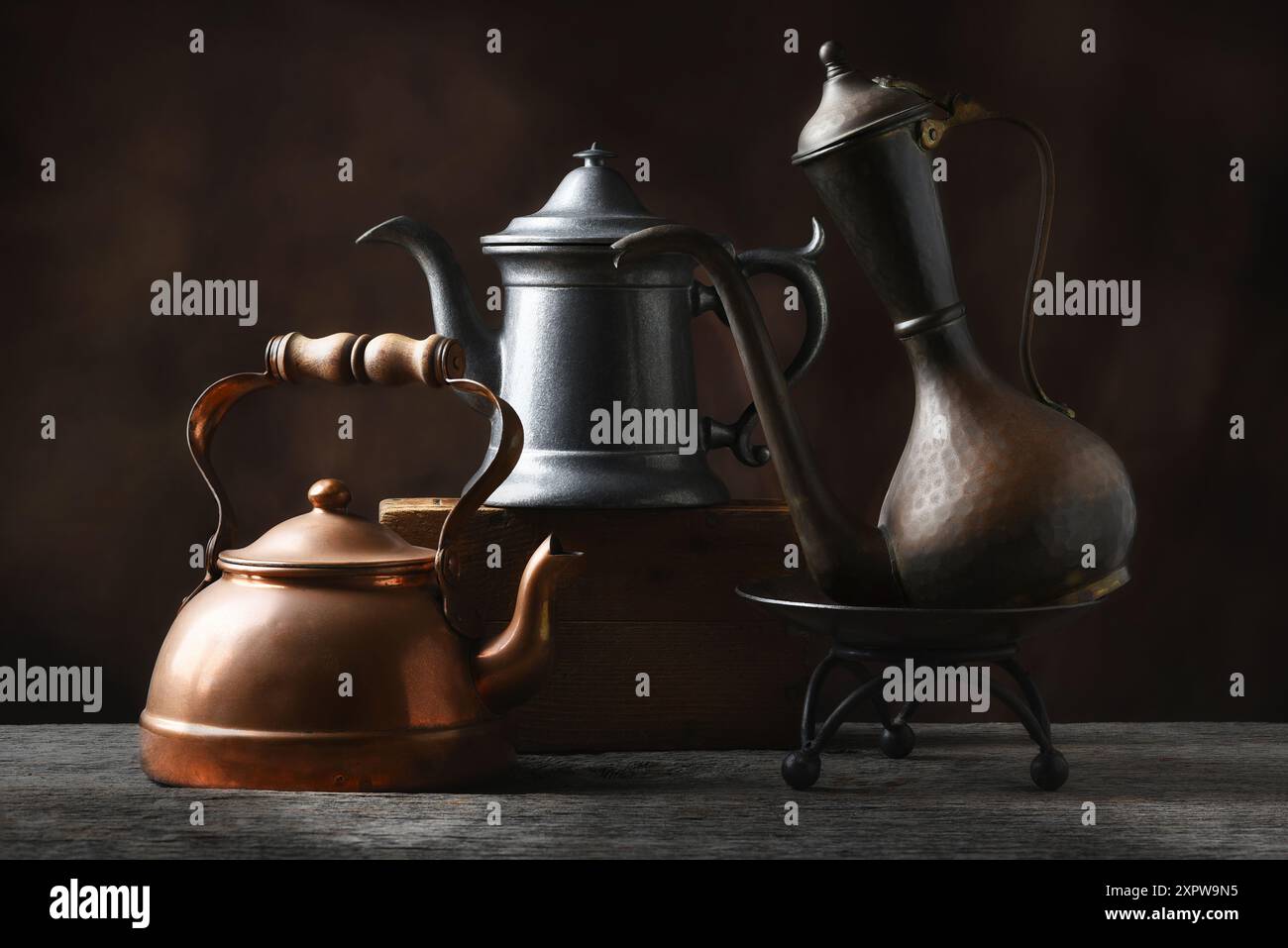 Three different tea pots on a rustic wood table with warm side light ...
