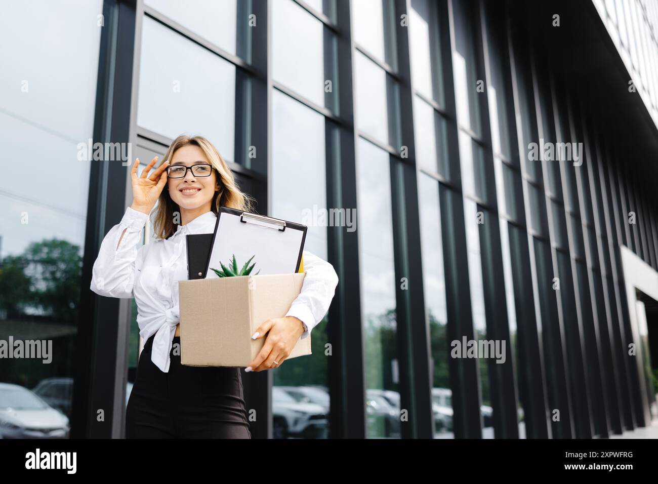 Caucasian businesswoman walking outdoors with box of stuff leaving ...