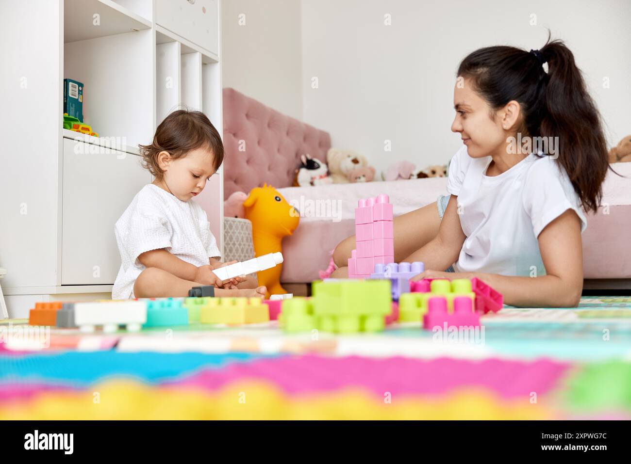 cute baby girl and her loving mother playing with toy bricks in the ...