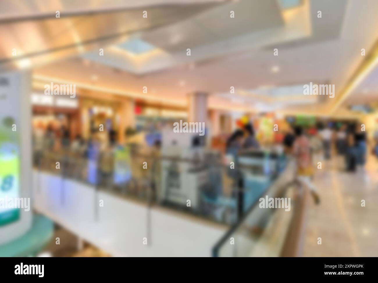 A blurred image of a busy shopping mall with many people walking around ...