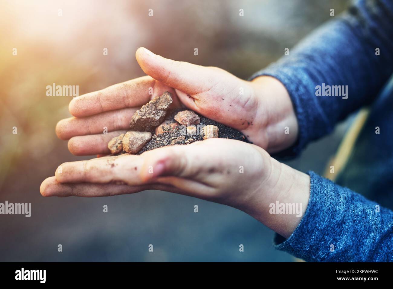 Child, hands and sand with stones in garden for sensory play to explore ...