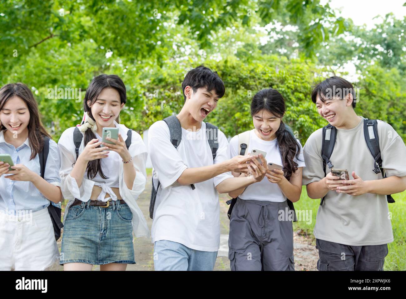 Happy teenagers having fun while using mobile phone in school Stock ...