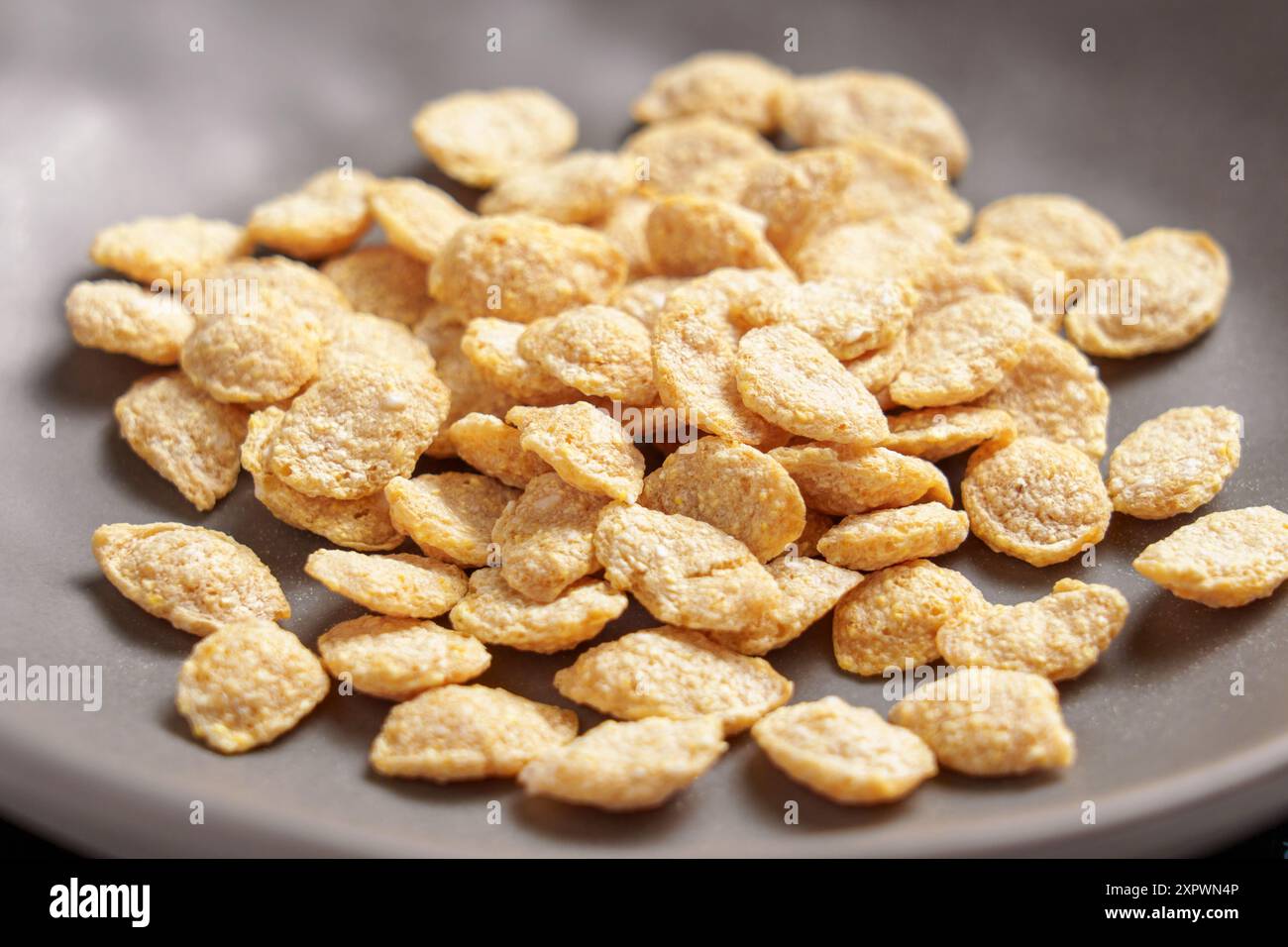 Nutritious breakfast cereal flakes fall while cooking in gray bowl ...