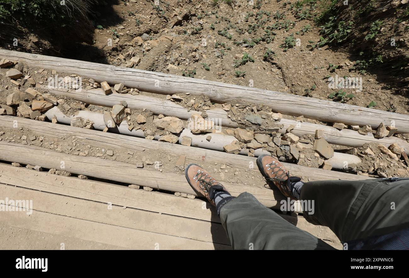 legs with hiking boots on the feet of the explorer as he walks on a ...