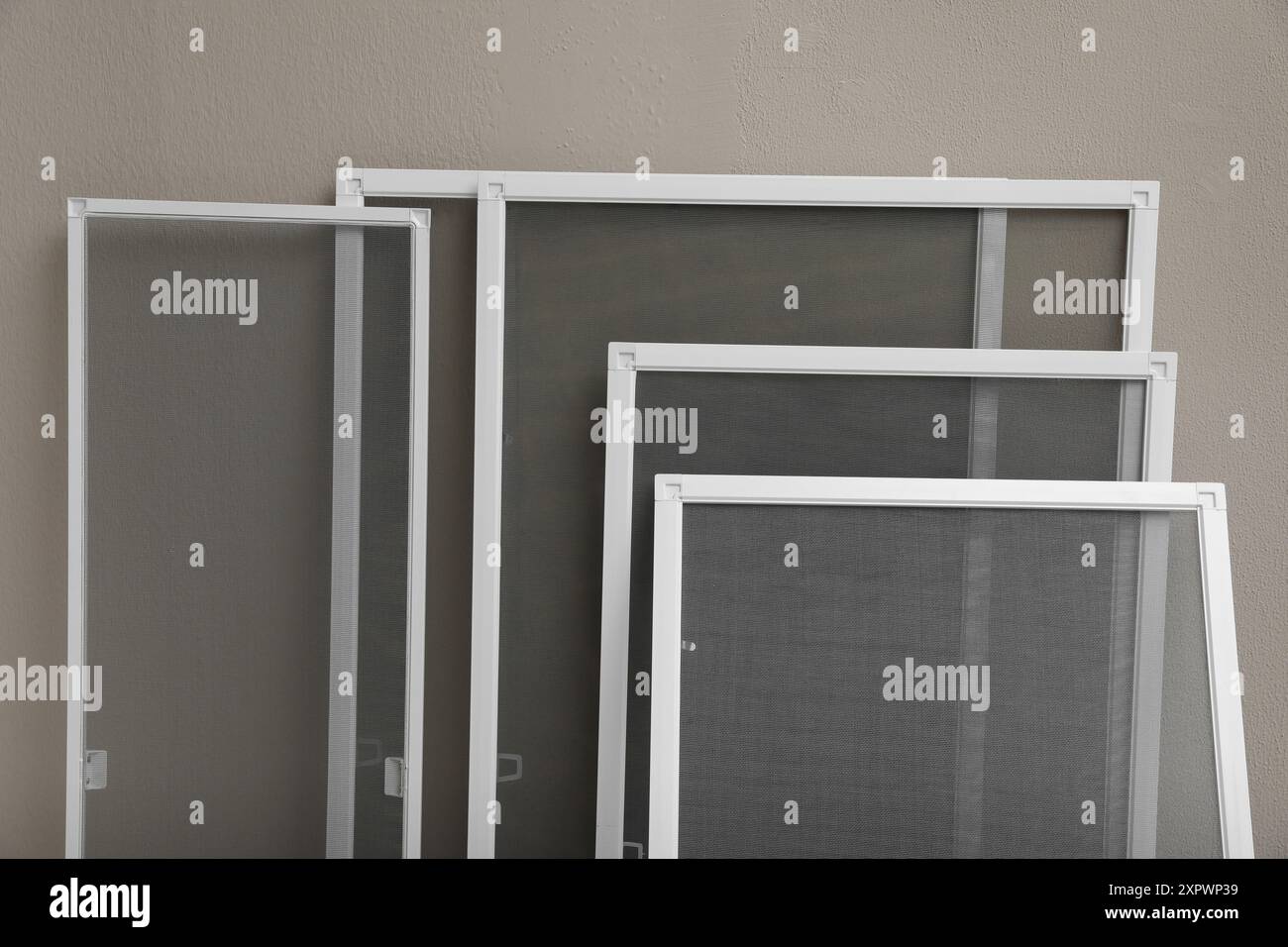 Set of window screens near beige wall Stock Photo - Alamy