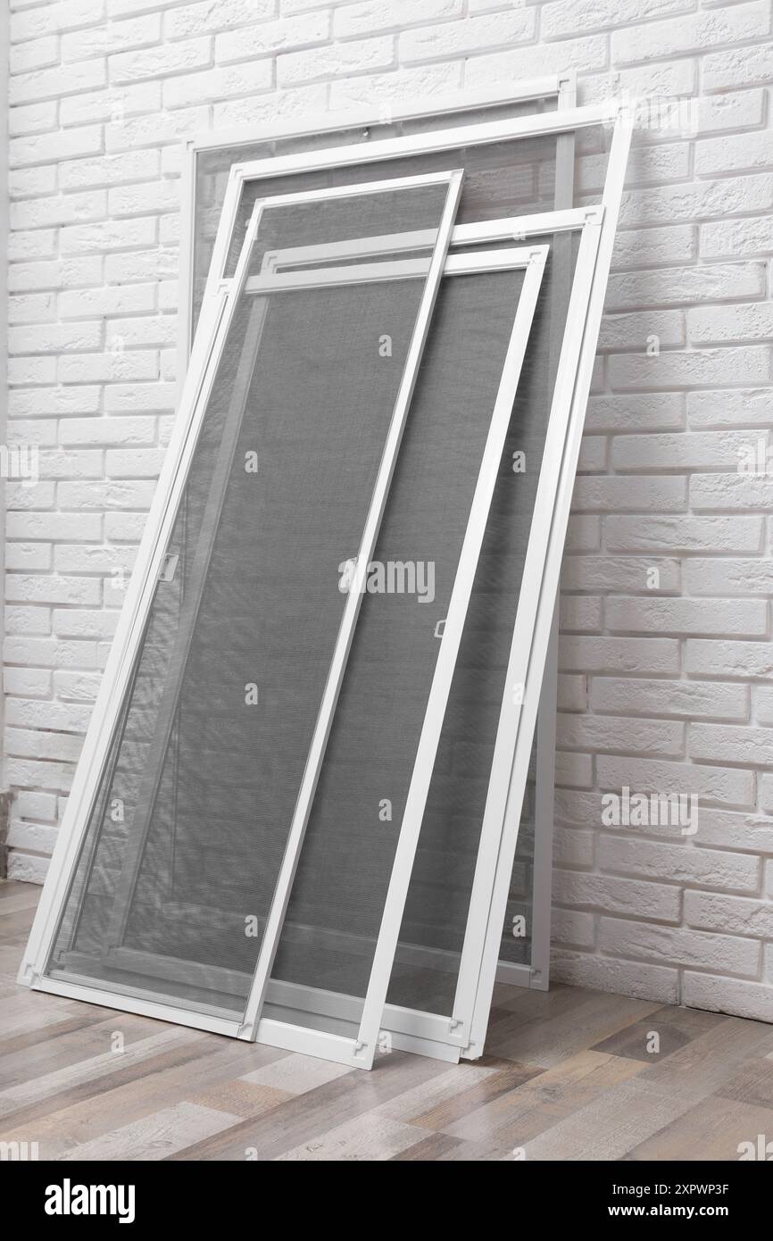 Set of window screens near white brick wall indoors Stock Photo - Alamy