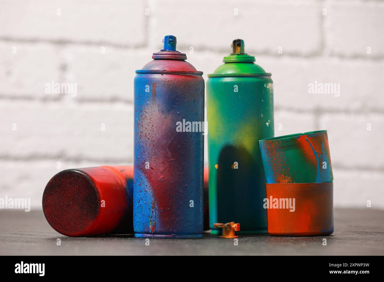 Many spray paint cans on gray surface against white brick wall Stock ...