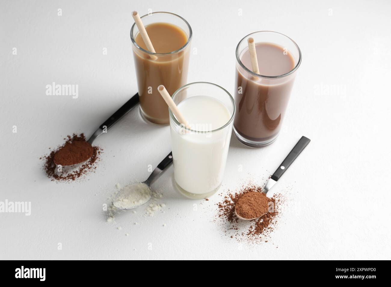 Delicious protein shakes in glasses and spoons with powder on white ...