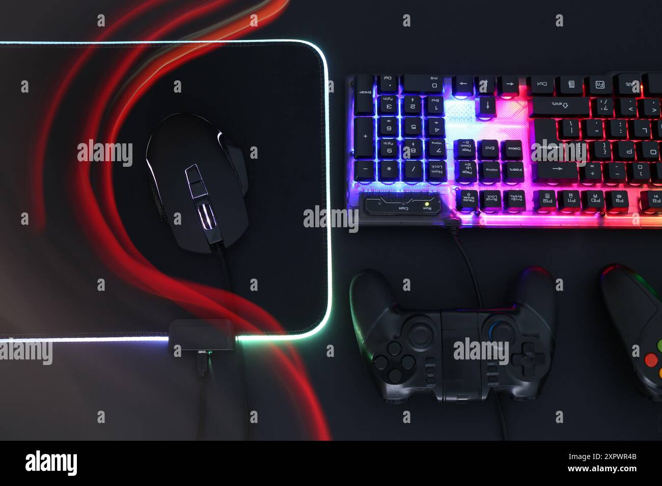 Computer mouse, RGB keyboard and game controllers in neon lights on ...