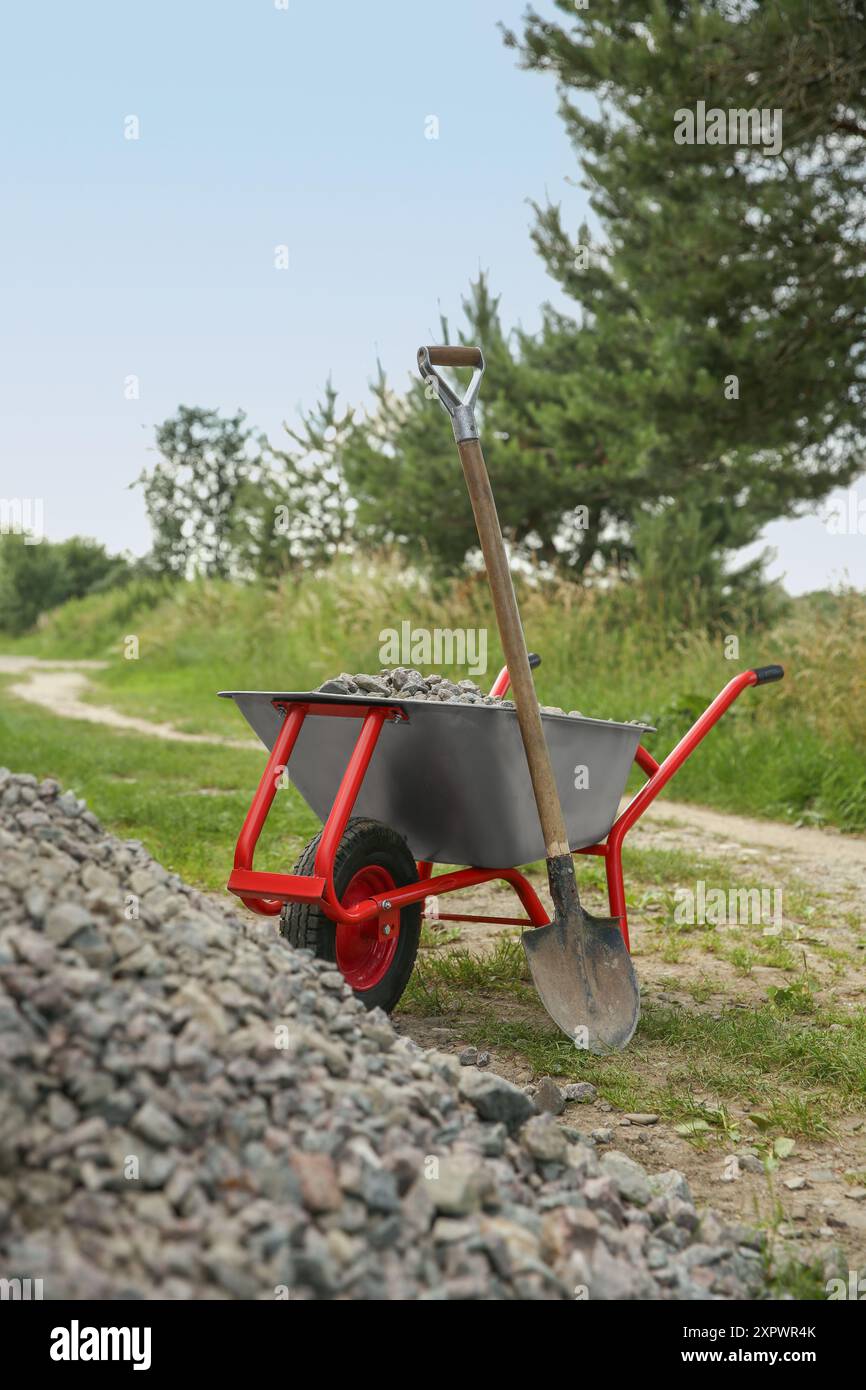 Wheelbarrow full of stones and shovel outdoors Stock Photo - Alamy
