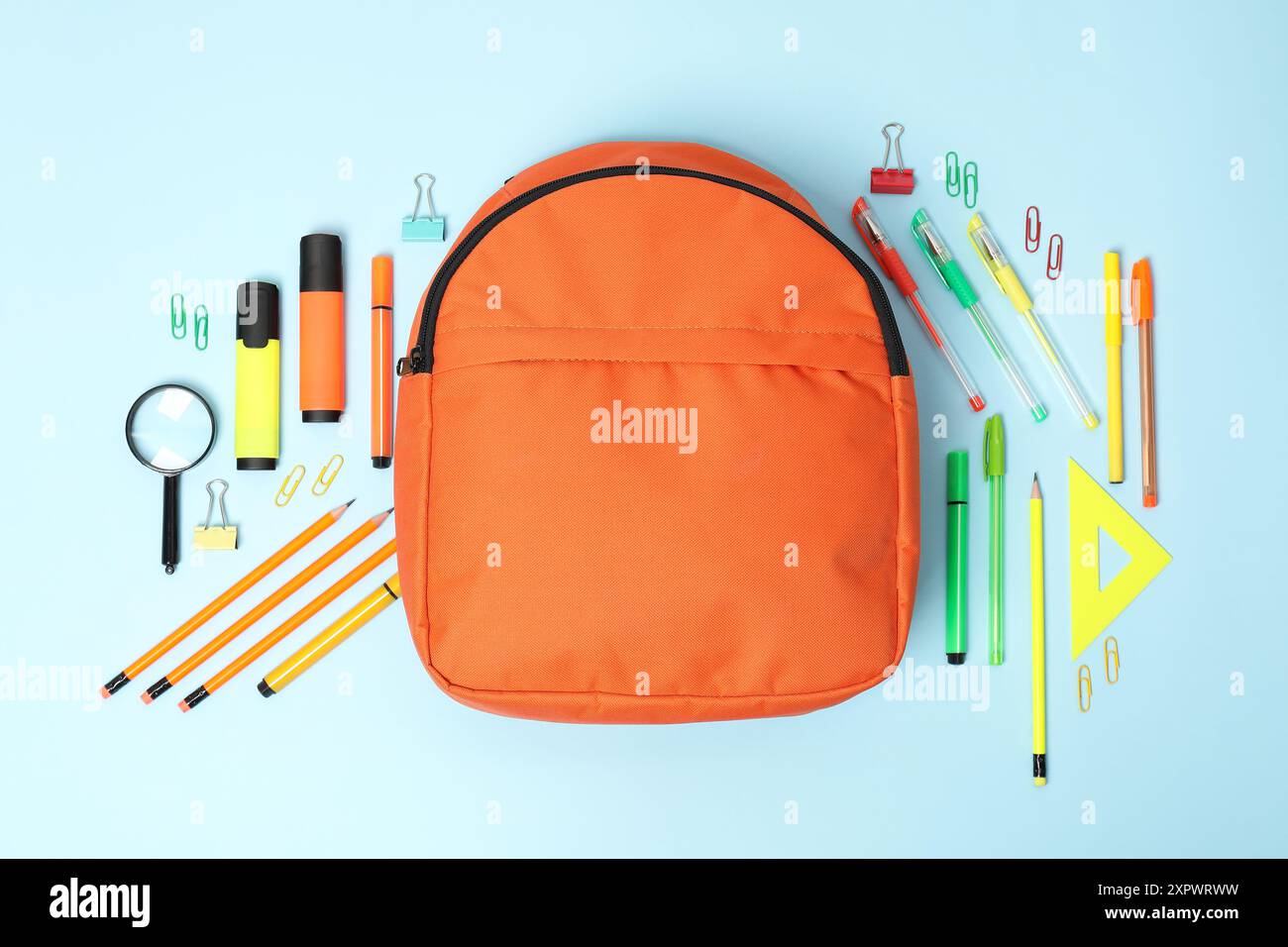 Orange backpack and different school supplies on light blue background ...