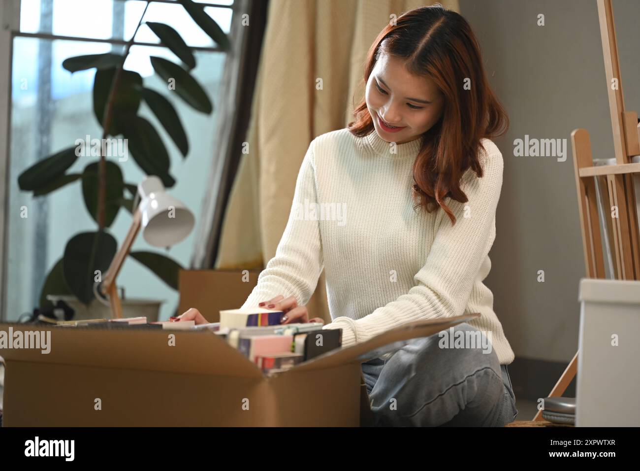 Beautiful young woman unpacking boxes and arranging stuff in her new ...