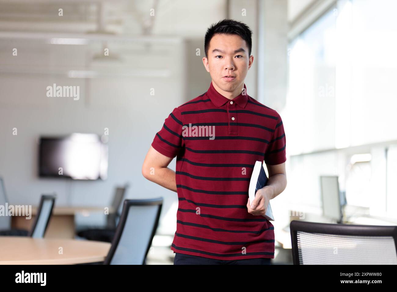A nerdy and awkward teenage male college student standing in a library ...