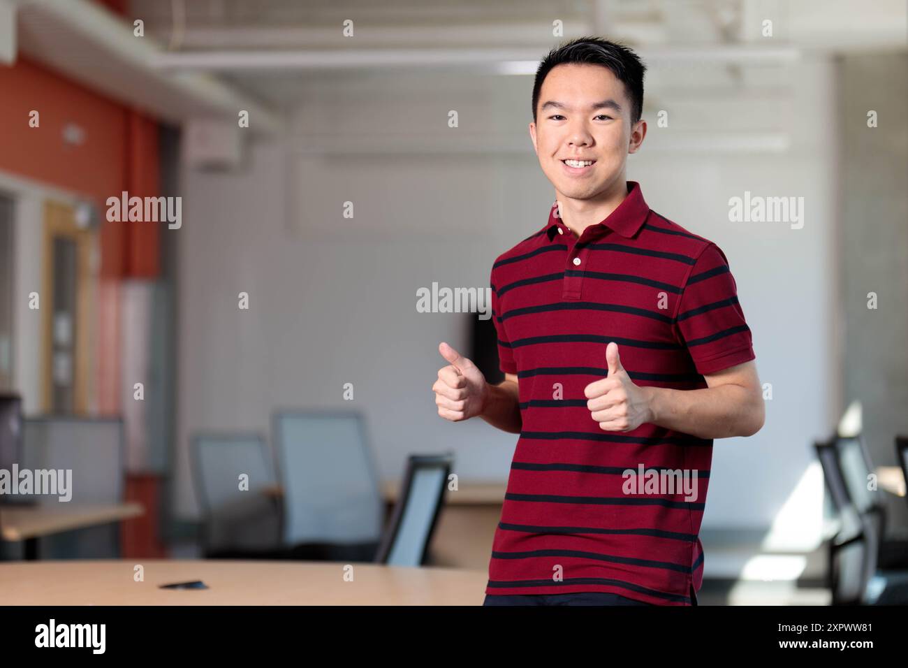 A young teenaged male college student intern standing in a office or ...