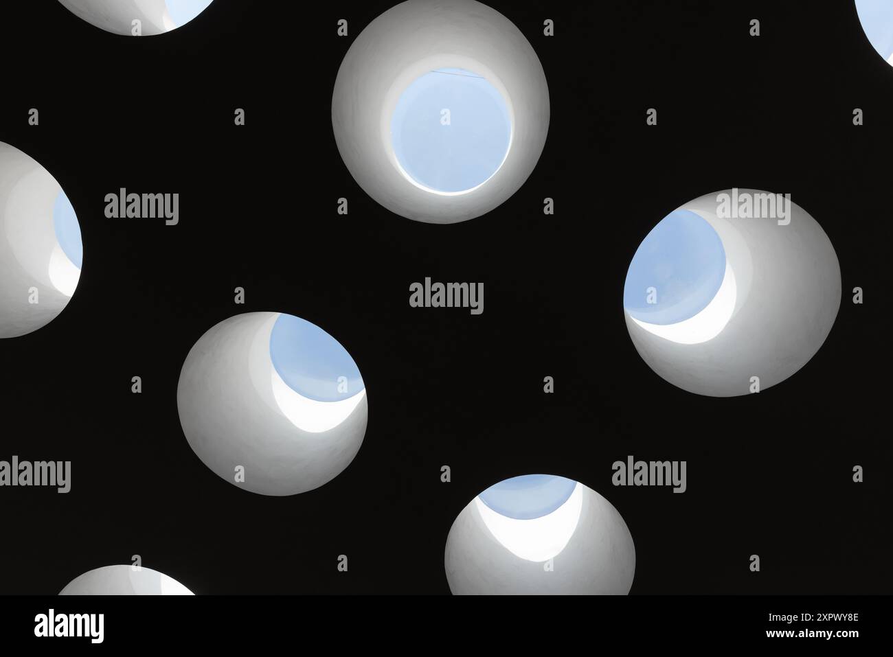 Black ceiling and round skylight portals with bright blue sky behind ...