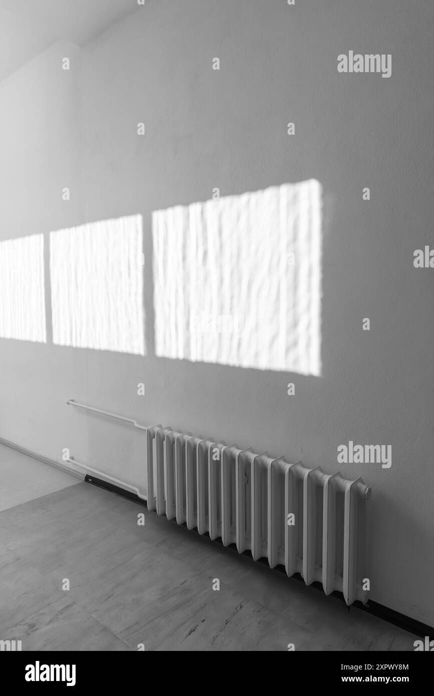 Empty corridor interior with water heating radiator and shadows pattern ...