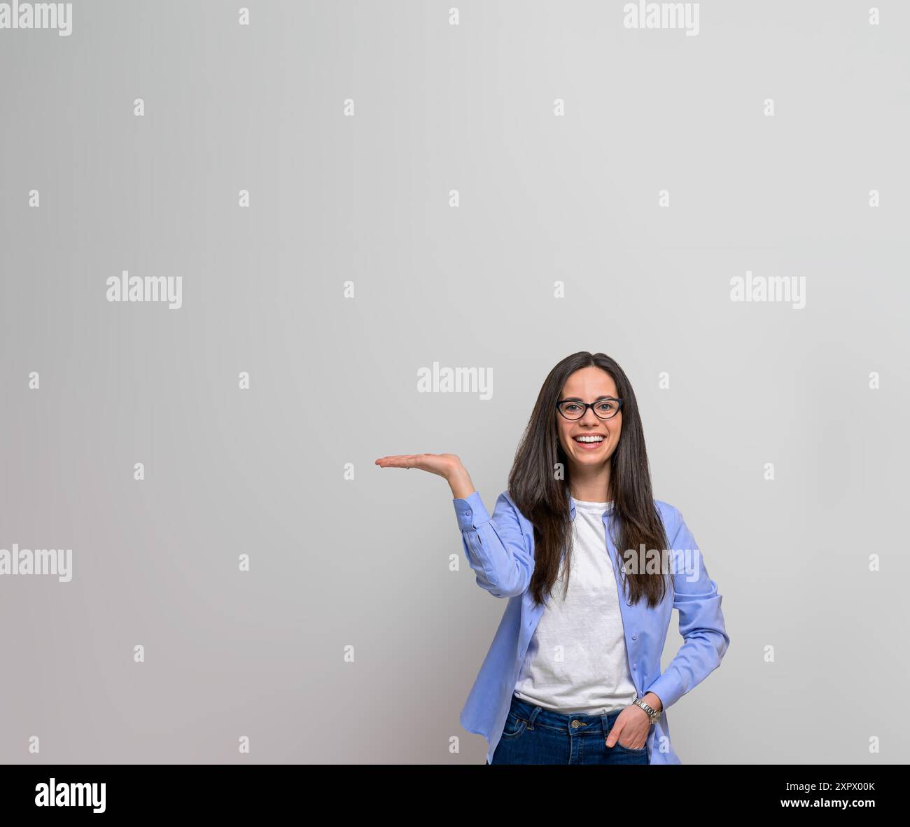 Portrait of smiling sales manager with hand in pocket presenting and ...