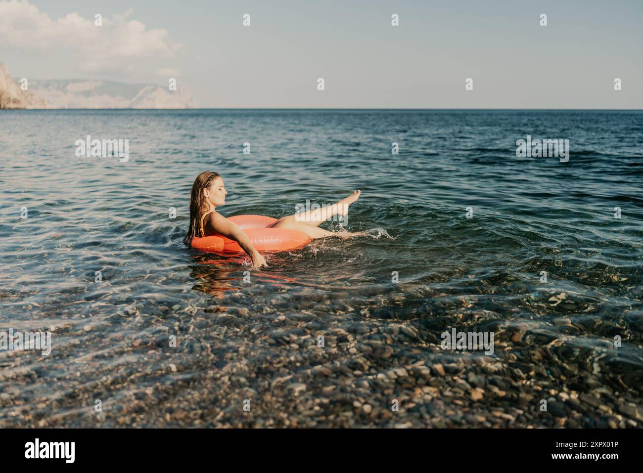 A woman is floating on a red inflatable raft in the ocean Stock Photo ...