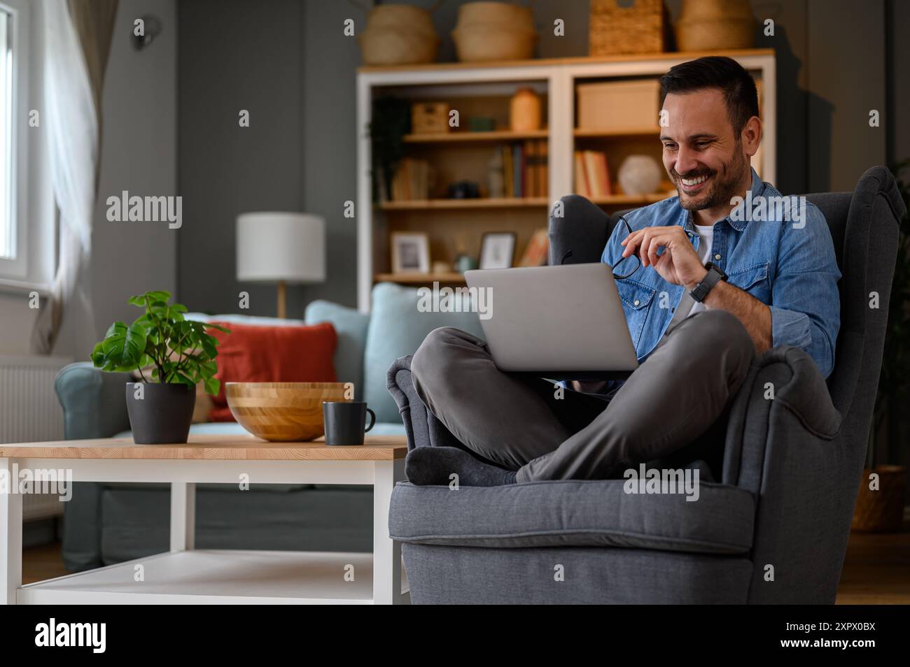 Happy Male Computer Programmer Working Over Laptop While Sitting Comfortably With Crossed Legs