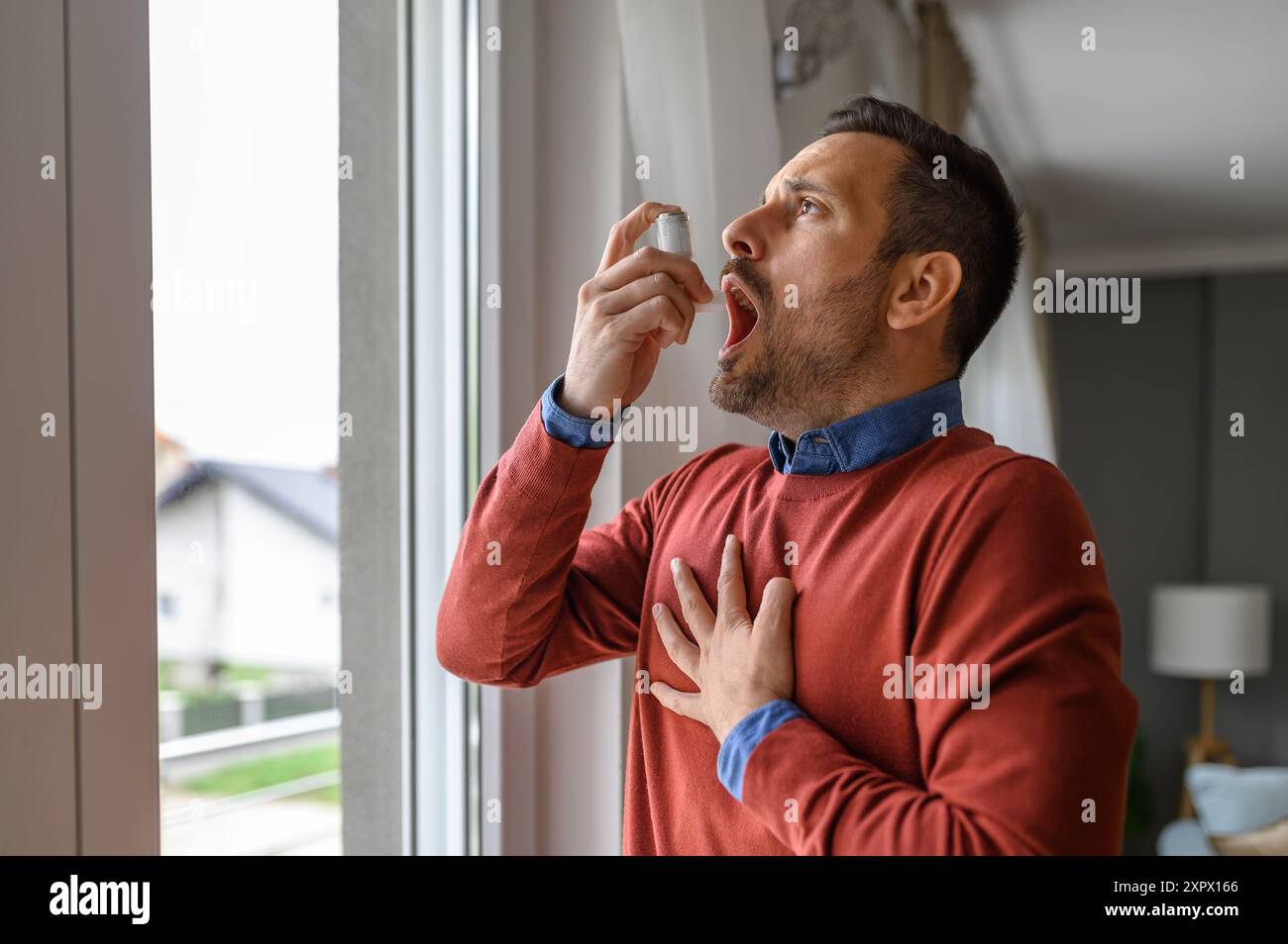 Asthmatic young man touching chest in pain and inhaling through asthma ...