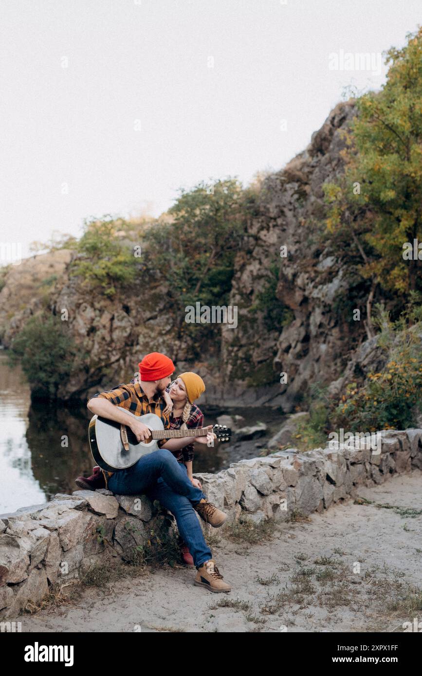 a guy in a bright hat plays the guitar with a girl against a background ...