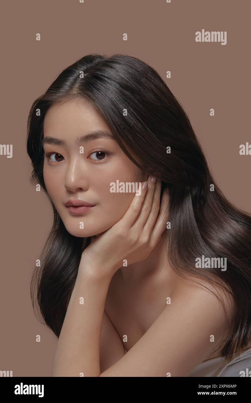 Charming young asian woman with a healthy clean skin leans hand at the ...