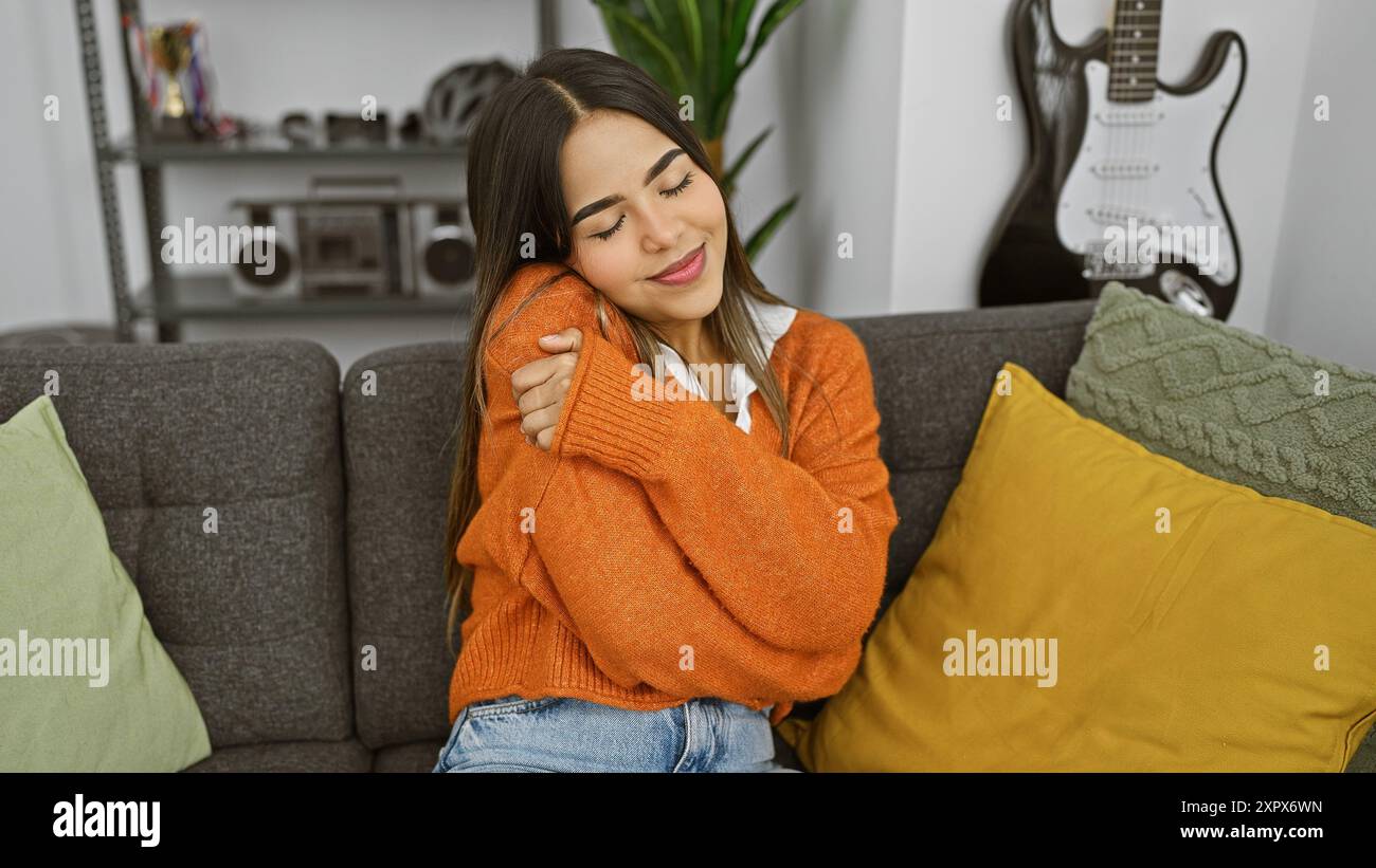 A contented young woman enjoys a cozy moment at home, semi-closed eyes ...